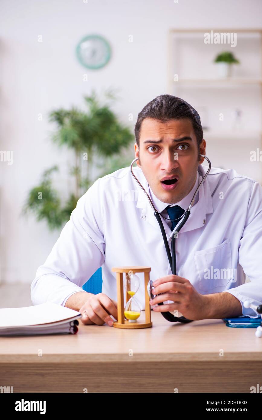 Young doctor in time management concept Stock Photo - Alamy