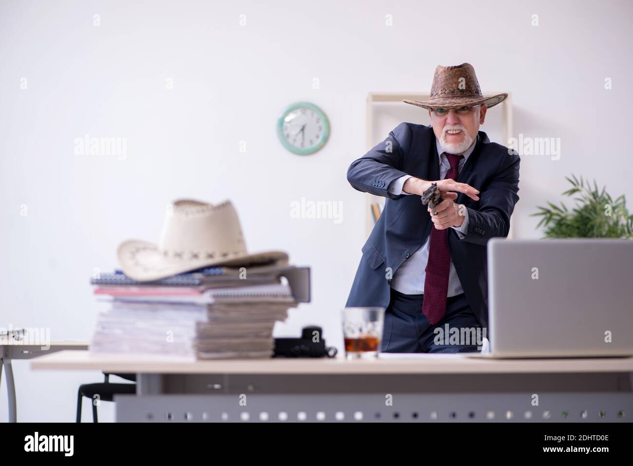 Funny old boss in cowboy hat in office Stock Photo - Alamy