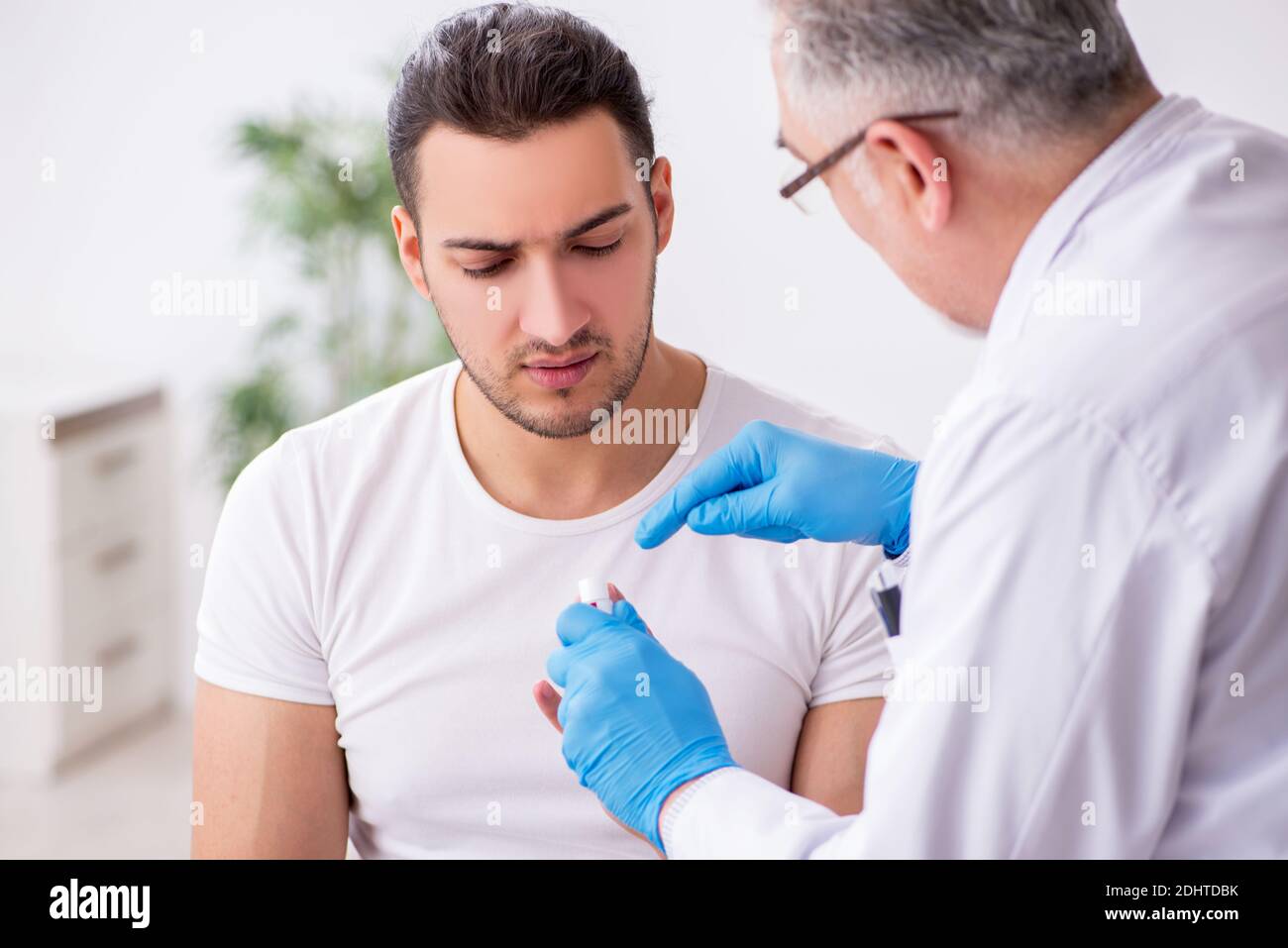Young man visiting old doctor dermatologist Stock Photo - Alamy