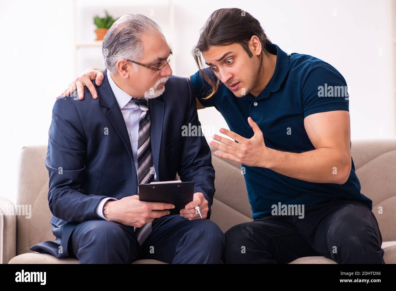 Young man visiting old psychologist Stock Photo - Alamy