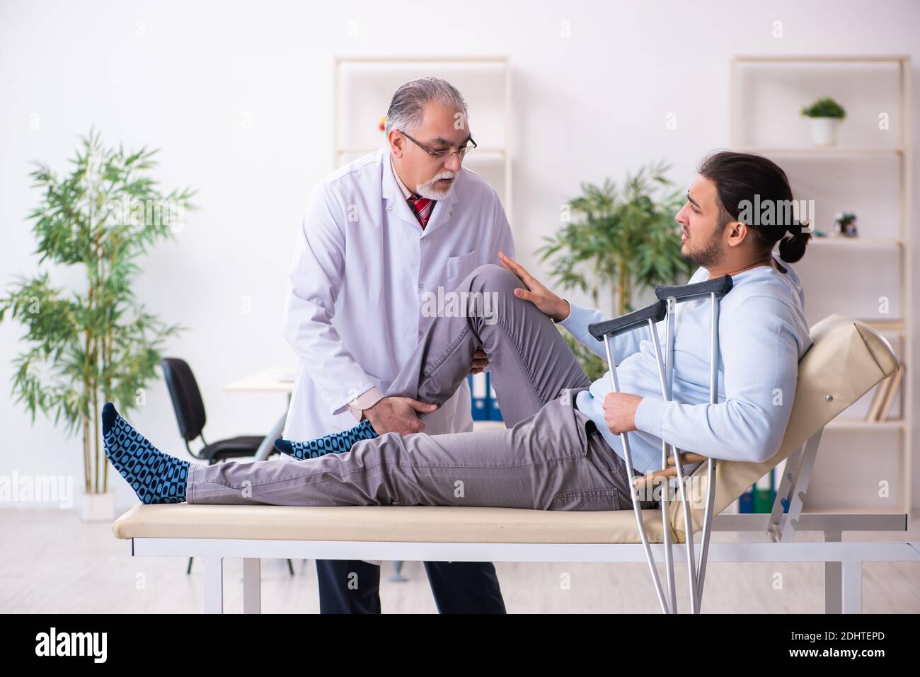Leg injured man visiting old doctor osteopath Stock Photo - Alamy