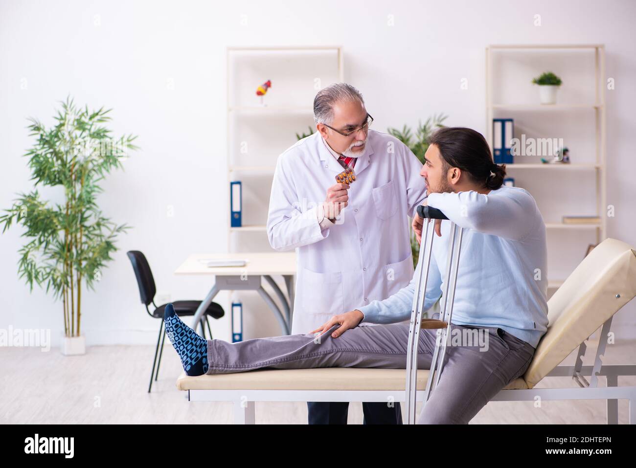 Leg injured man visiting old doctor osteopath Stock Photo - Alamy