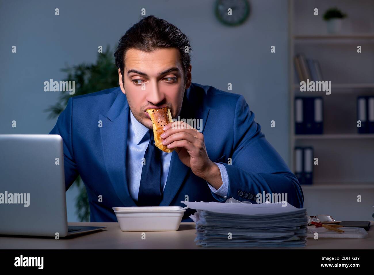 Hungry employee working late in office Stock Photo - Alamy