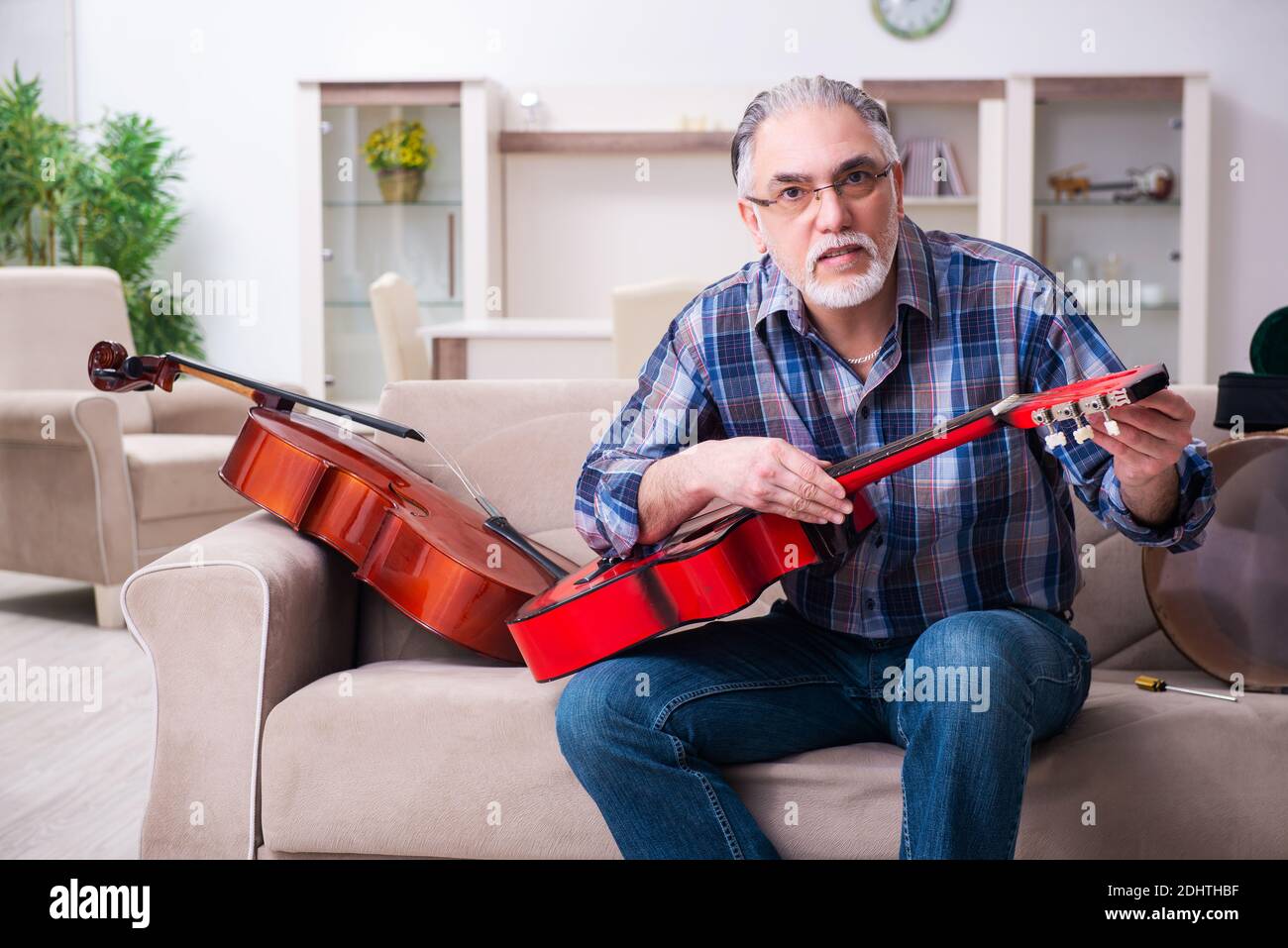 Senior repairman repairing musical instruments at home Stock Photo - Alamy