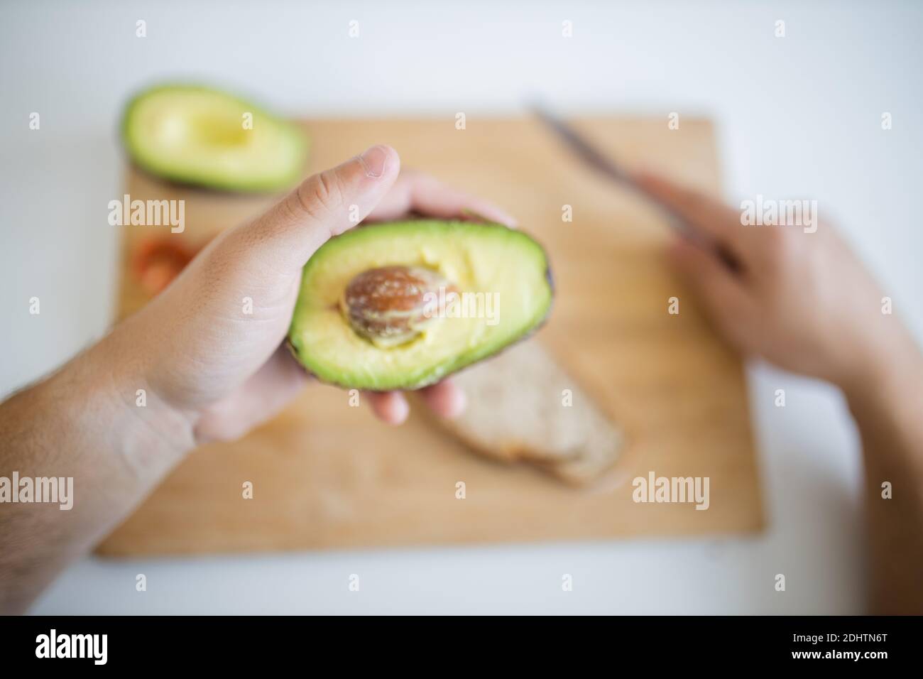 Male hand holding sliced avocado above a cutting board Stock Photo - Alamy
