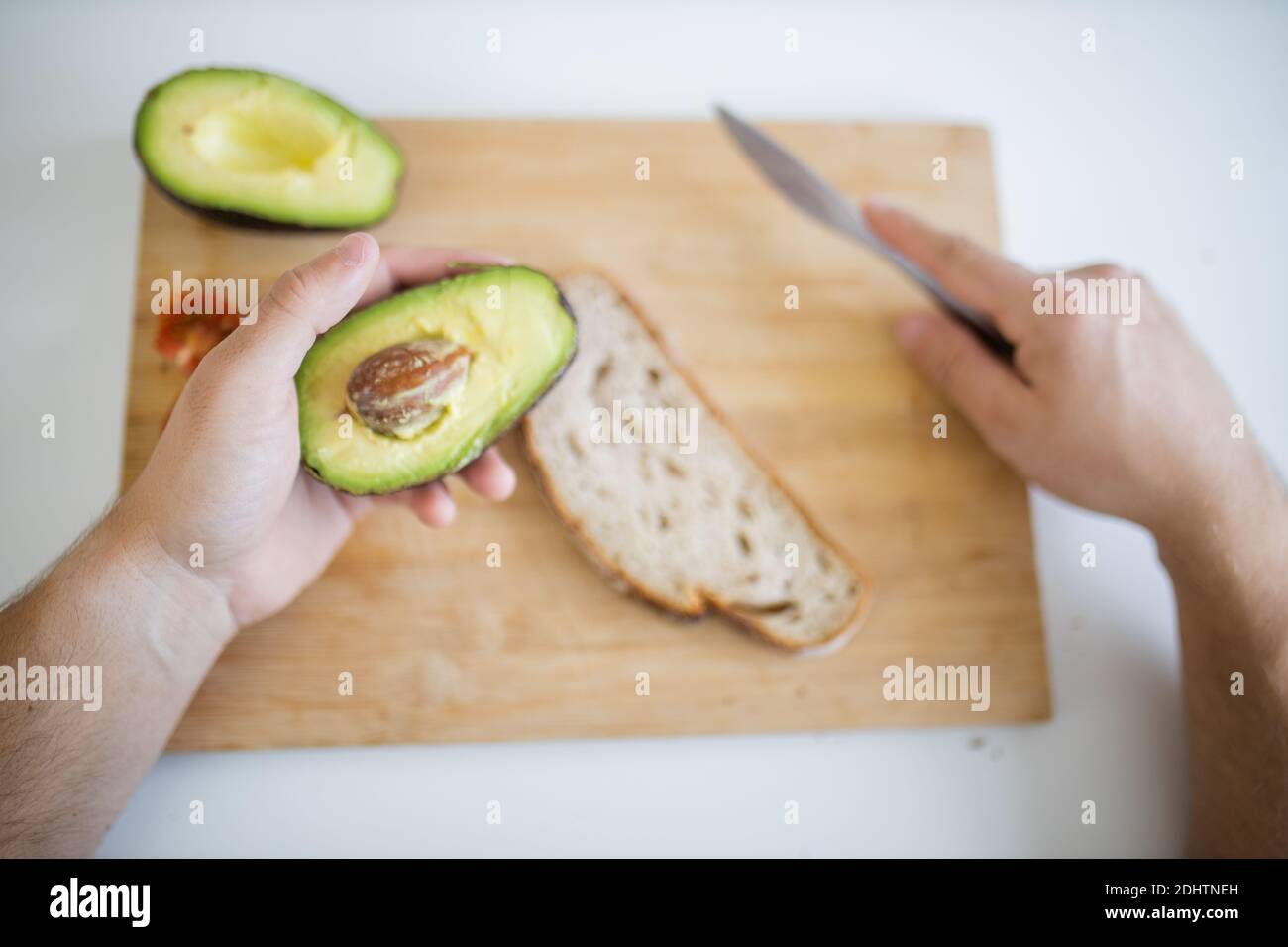 Male hand holding sliced avocado above a cutting board Stock Photo - Alamy