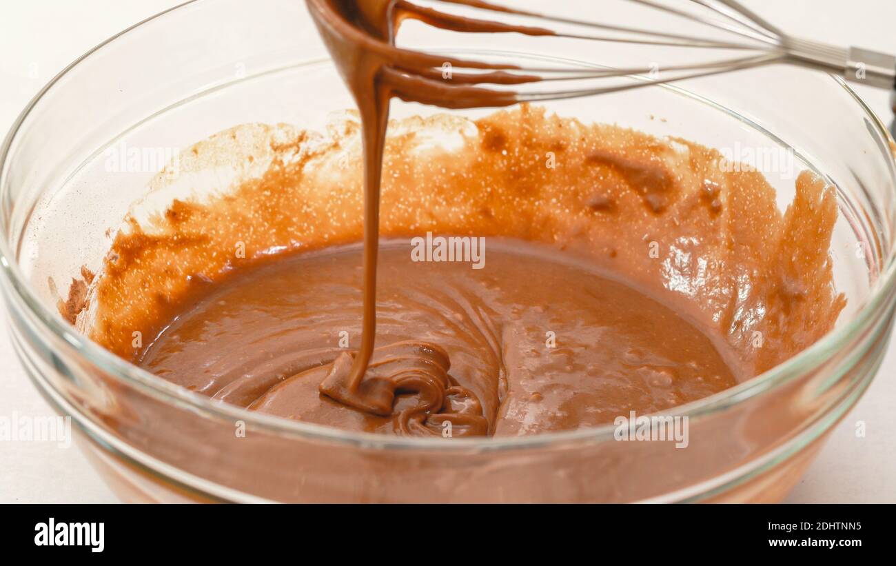 Close up of chocolate muffin batter in a glass bowl, mixing ingredients ...