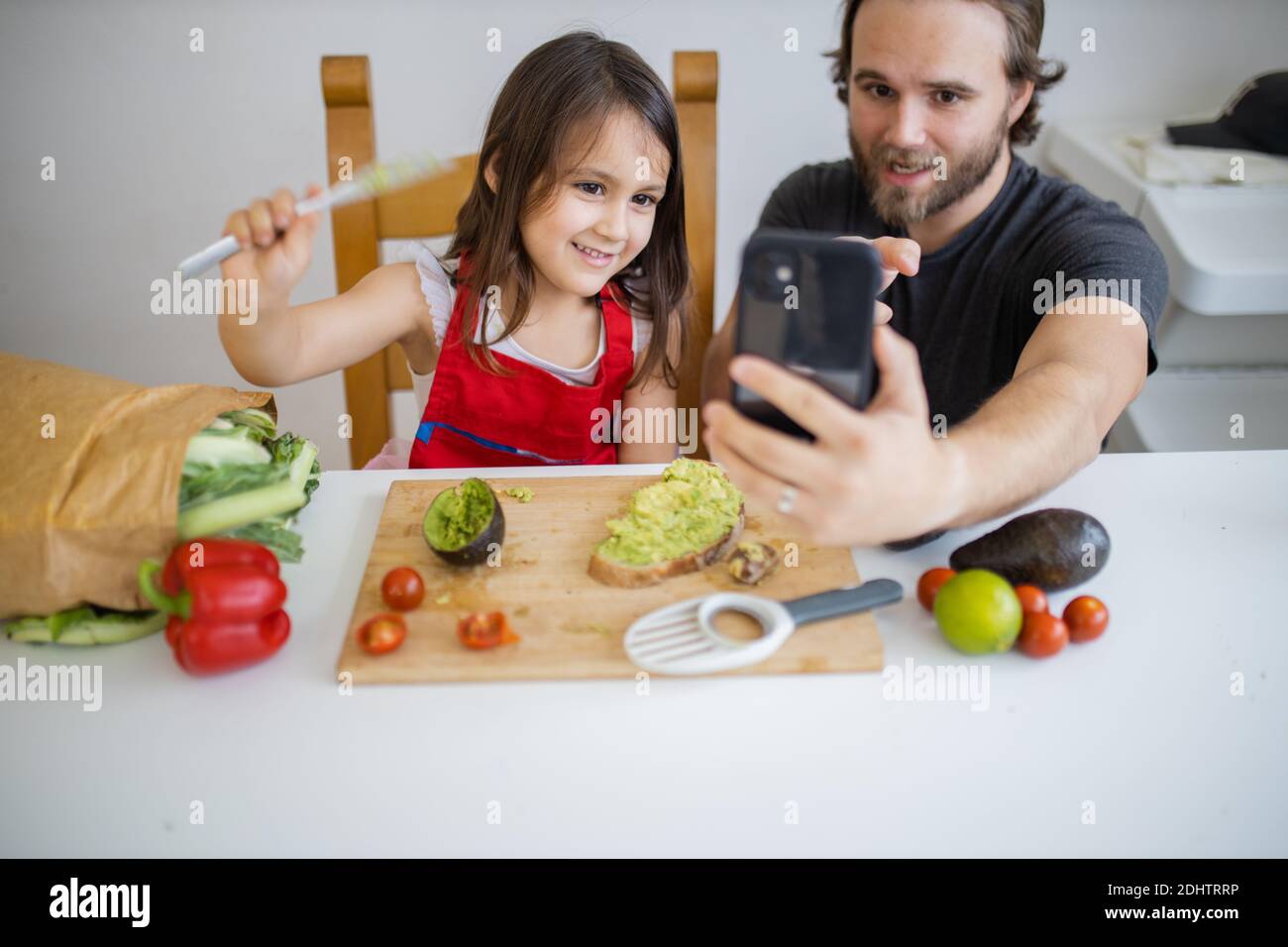 Father and daughter taking a selfie while making avocado toast Stock ...