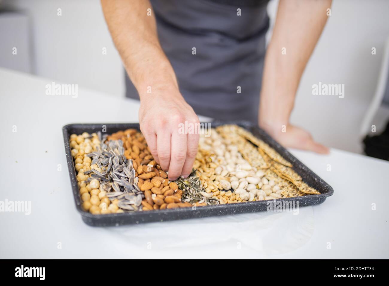Male hand picking seeds from a black tray with seeds and nuts Stock ...