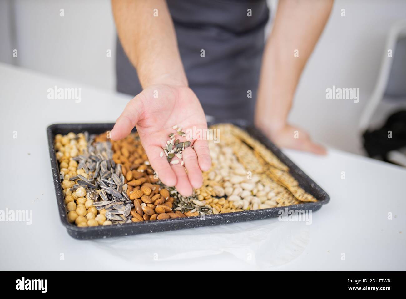 Male hand picking seeds from a black tray with seeds and nuts Stock ...