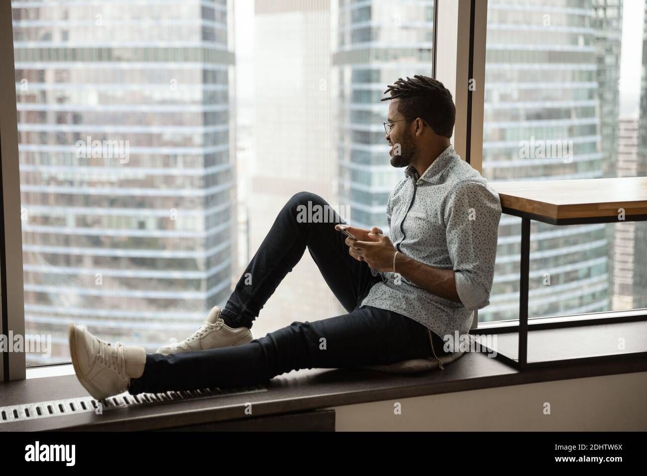 African American man relax on windowsill dreaming Stock Photo - Alamy