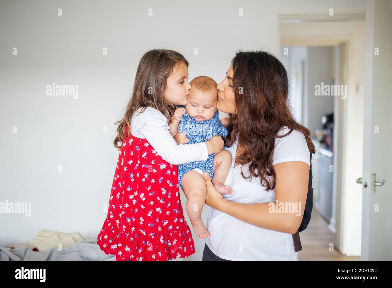 Happy woman and a little girl holding and kissing an adorable baby ...