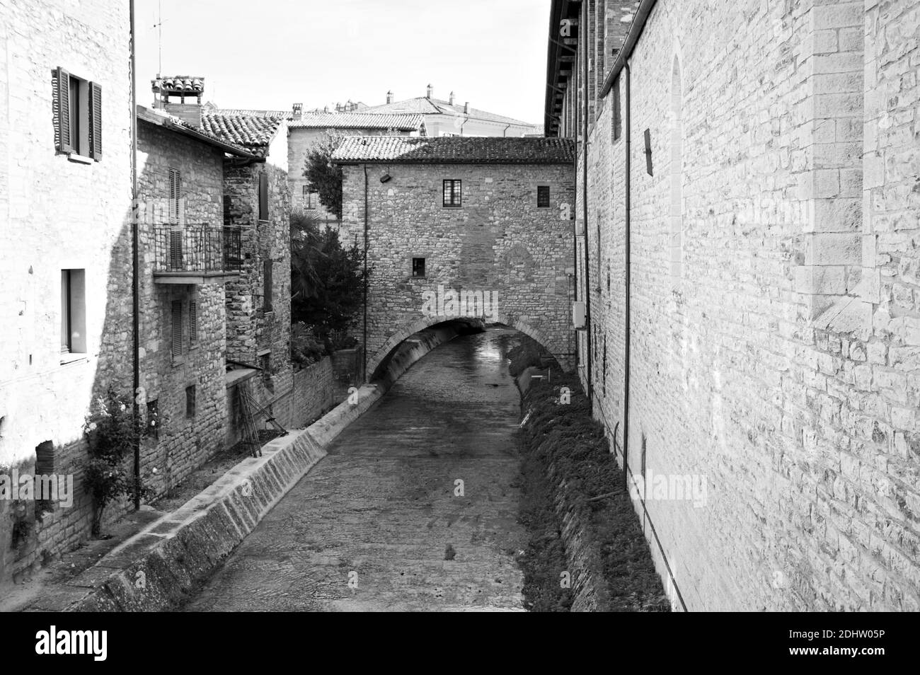 A medieval house with an arch under which a small stream flows in an ...