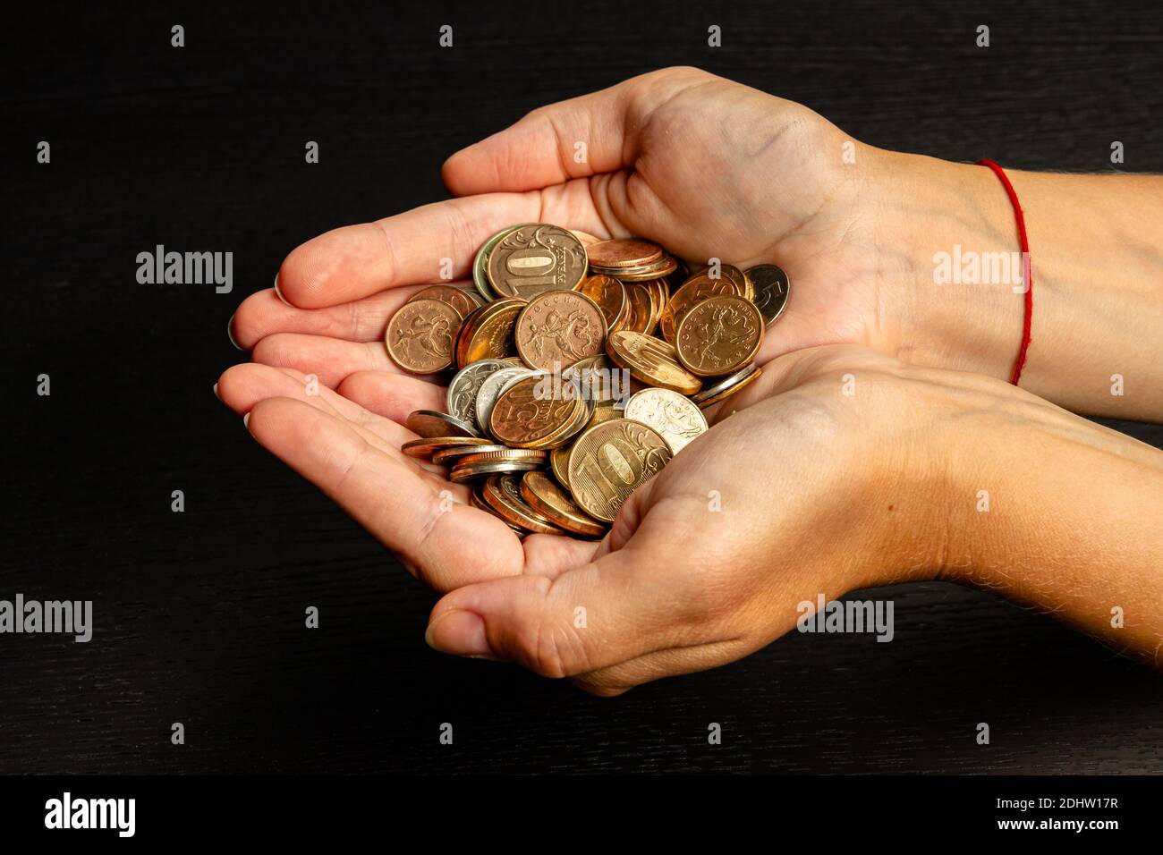 girl holding a handful of coins in her hands on a black table ...