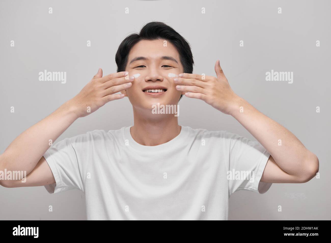 smiling man applying cream lotion on face Stock Photo - Alamy