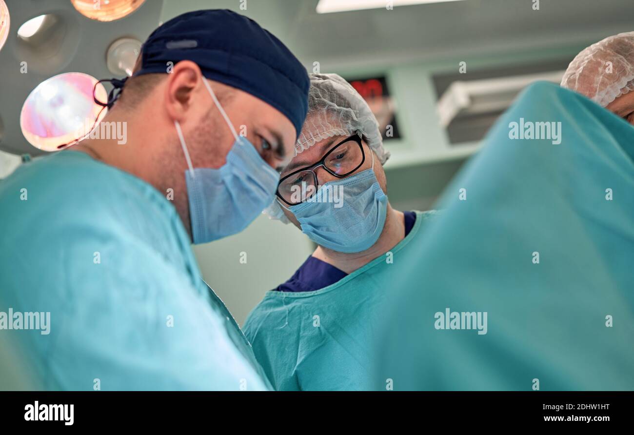Physicians in Surgery looking down at patient Stock Photo - Alamy