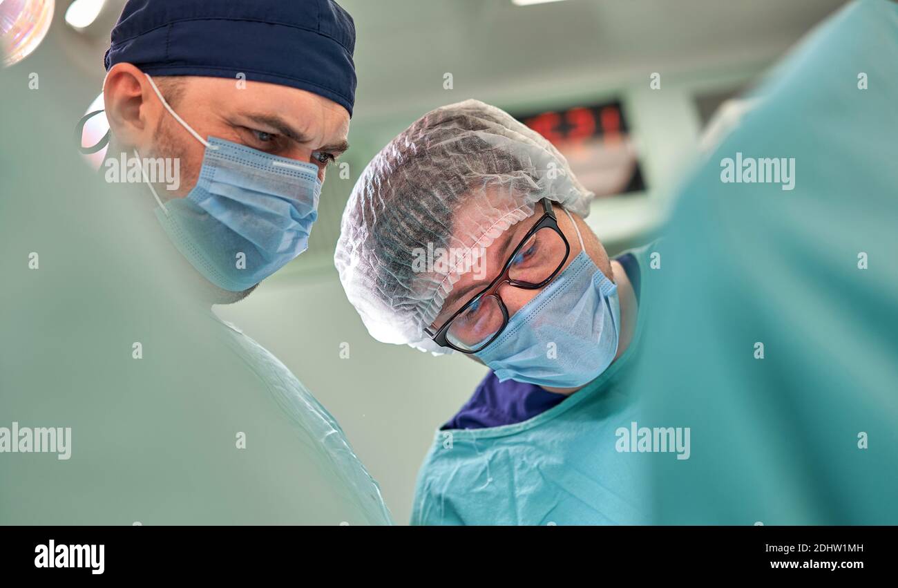 Physicians in Surgery looking down at patient Stock Photo - Alamy