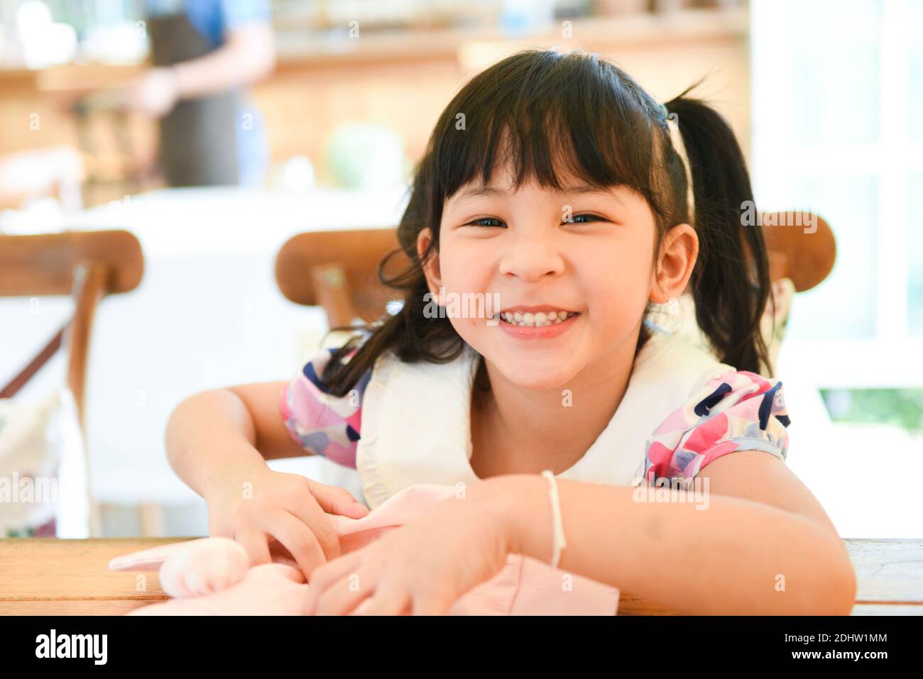 Little asian child girl have fun with a happy smiling face at the cafe ...