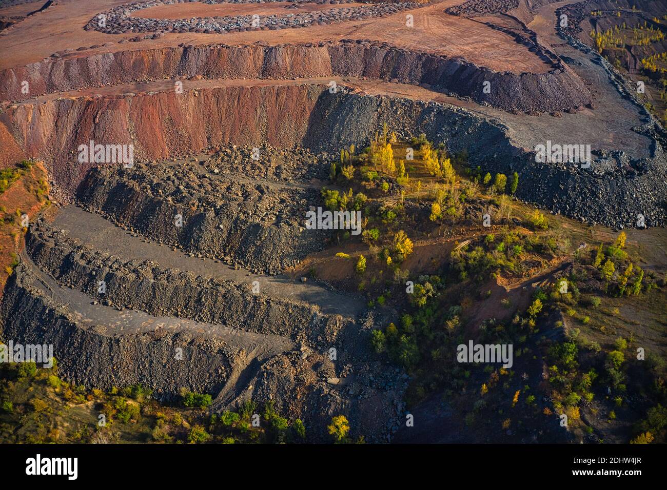 Huge mounds of waste iron ore near the quarry. Belaz trucks driving in ...