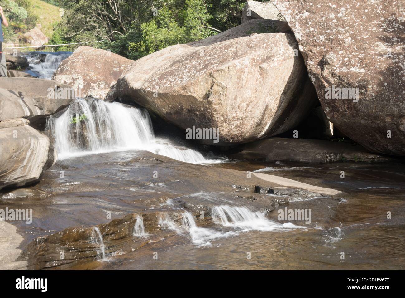 A beautiful waterfall in a mountain stream with engulfing rocks and ...