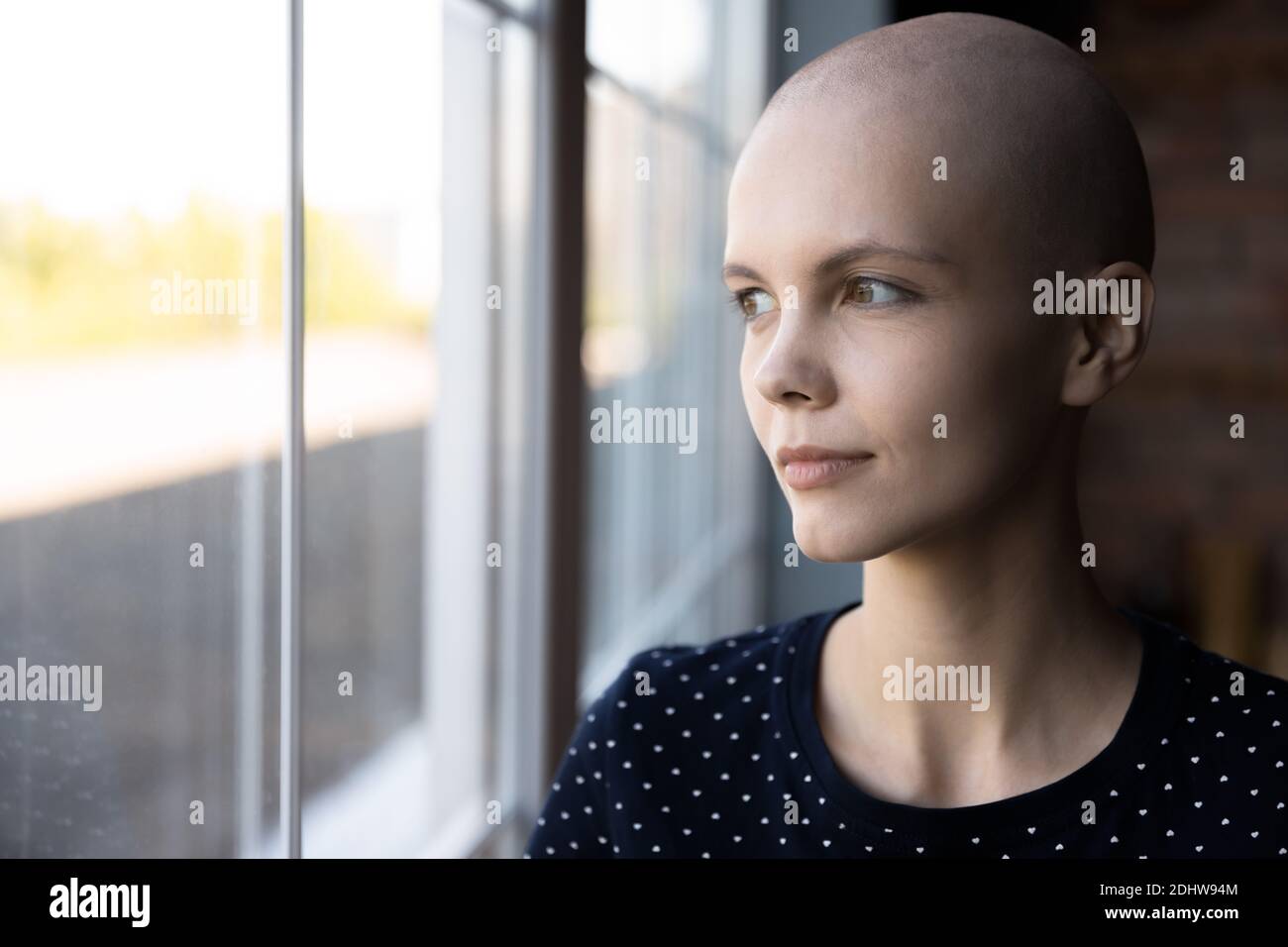 Close up thoughtful hairless woman cancer patient looking in window ...