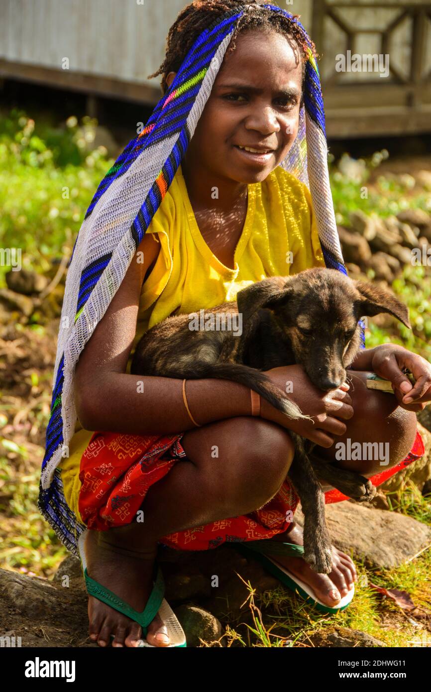 Dani girl in western clothes with het pet dog in a village in the ...