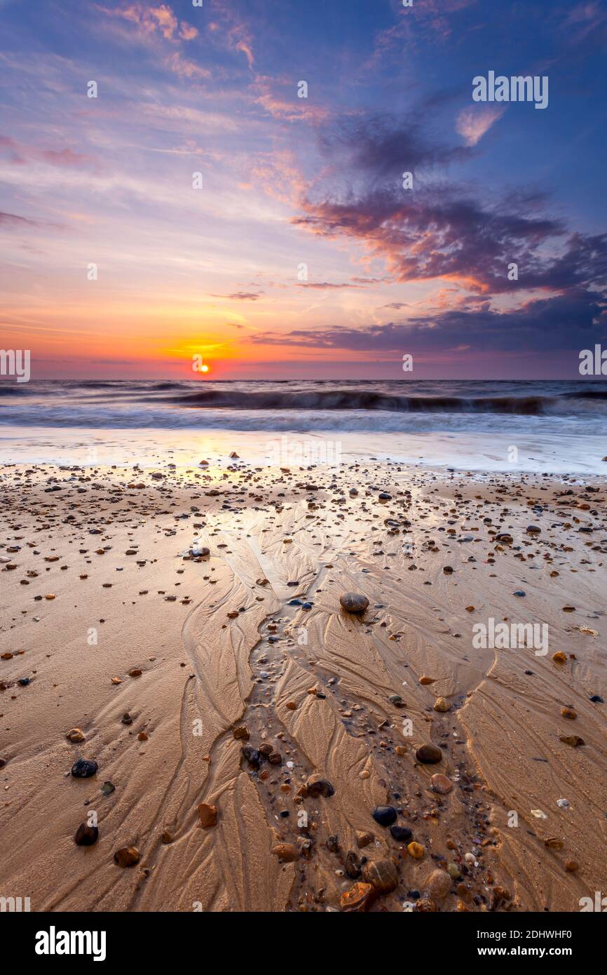 Water flows across the beach into the sea creating lines in the sand as ...