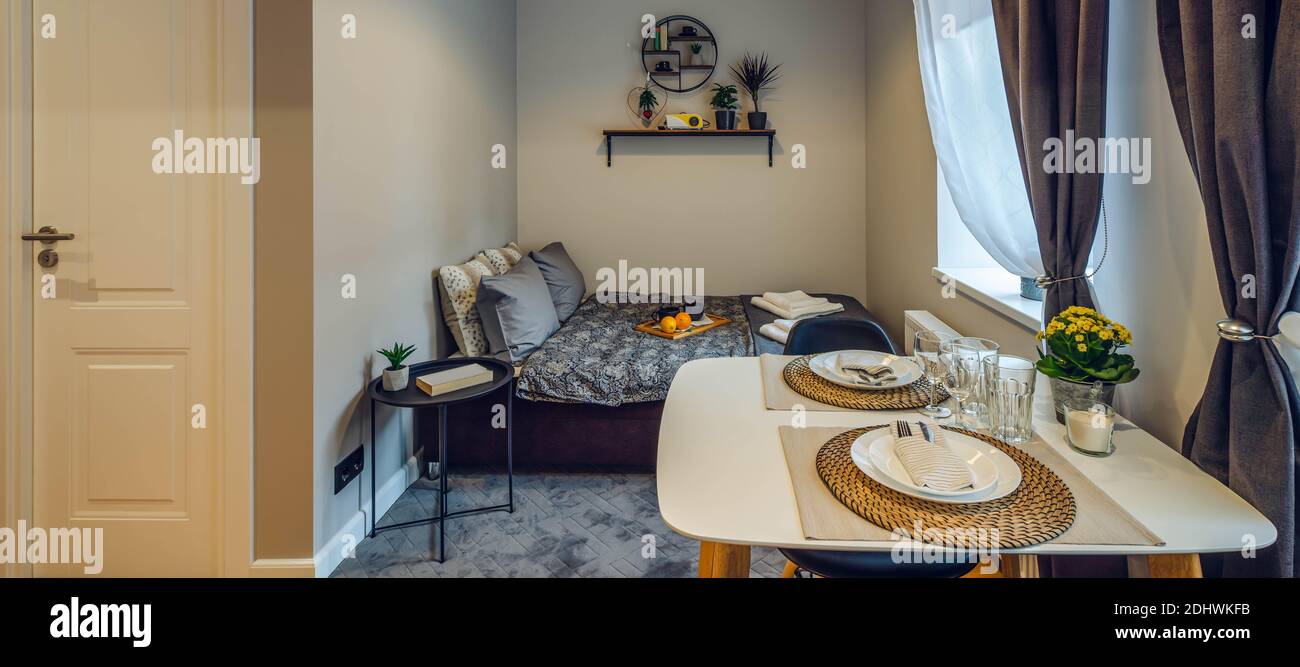 Modern interior of small studio apartment. Wooden dinner table. Cozy ...
