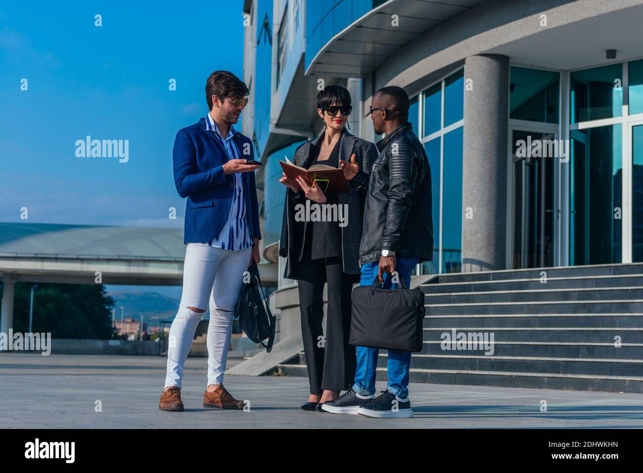 Business team of three multi-ethnic people working outside modern ...