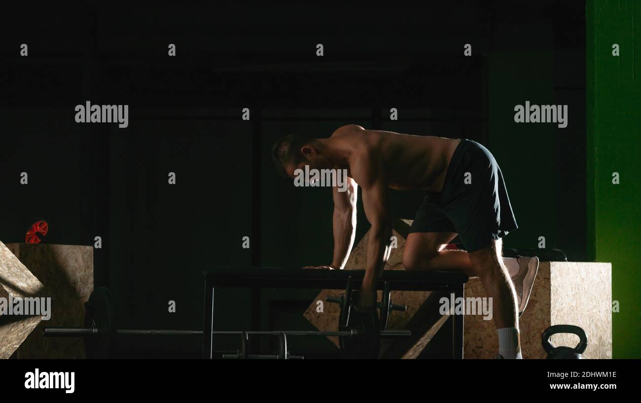 Good looking young man doing triceps dumbbell kickback exercises with ...