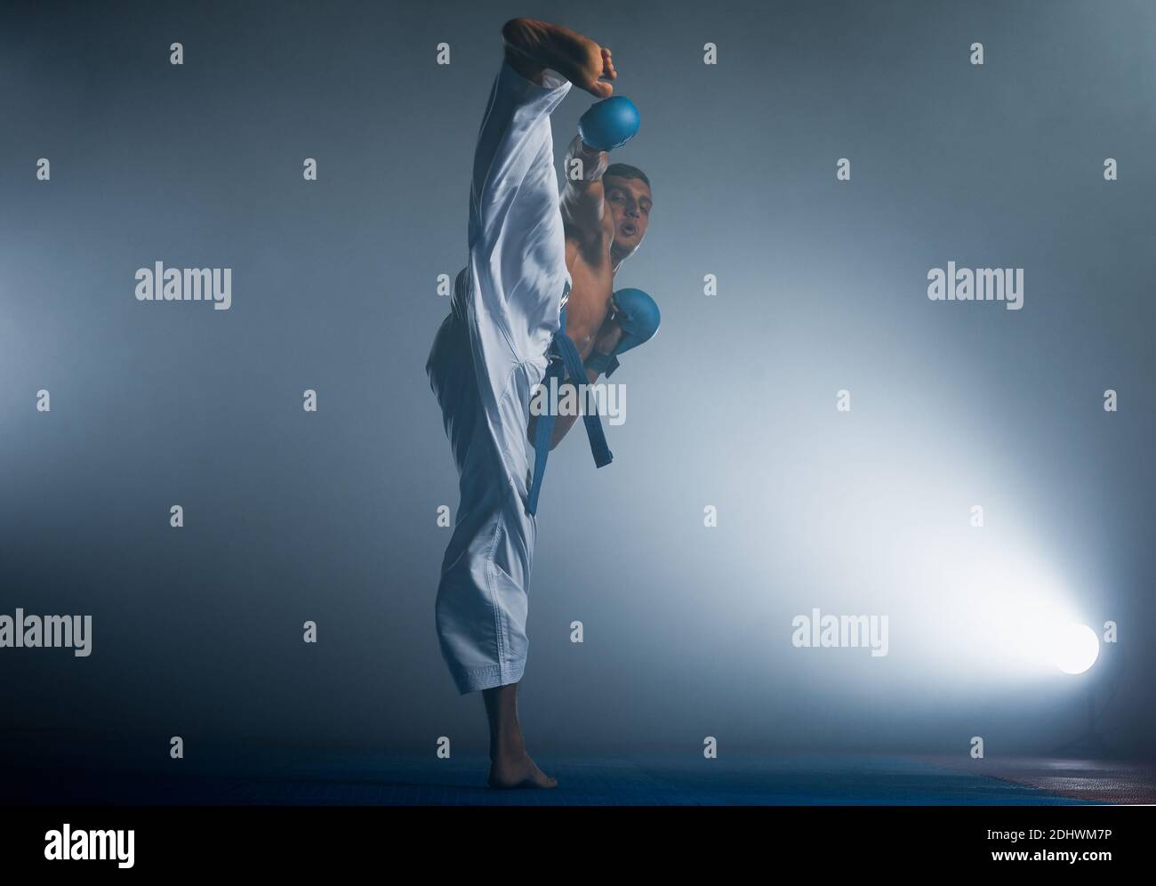 Male karate fighter performing kick isolated on dark background in the ...