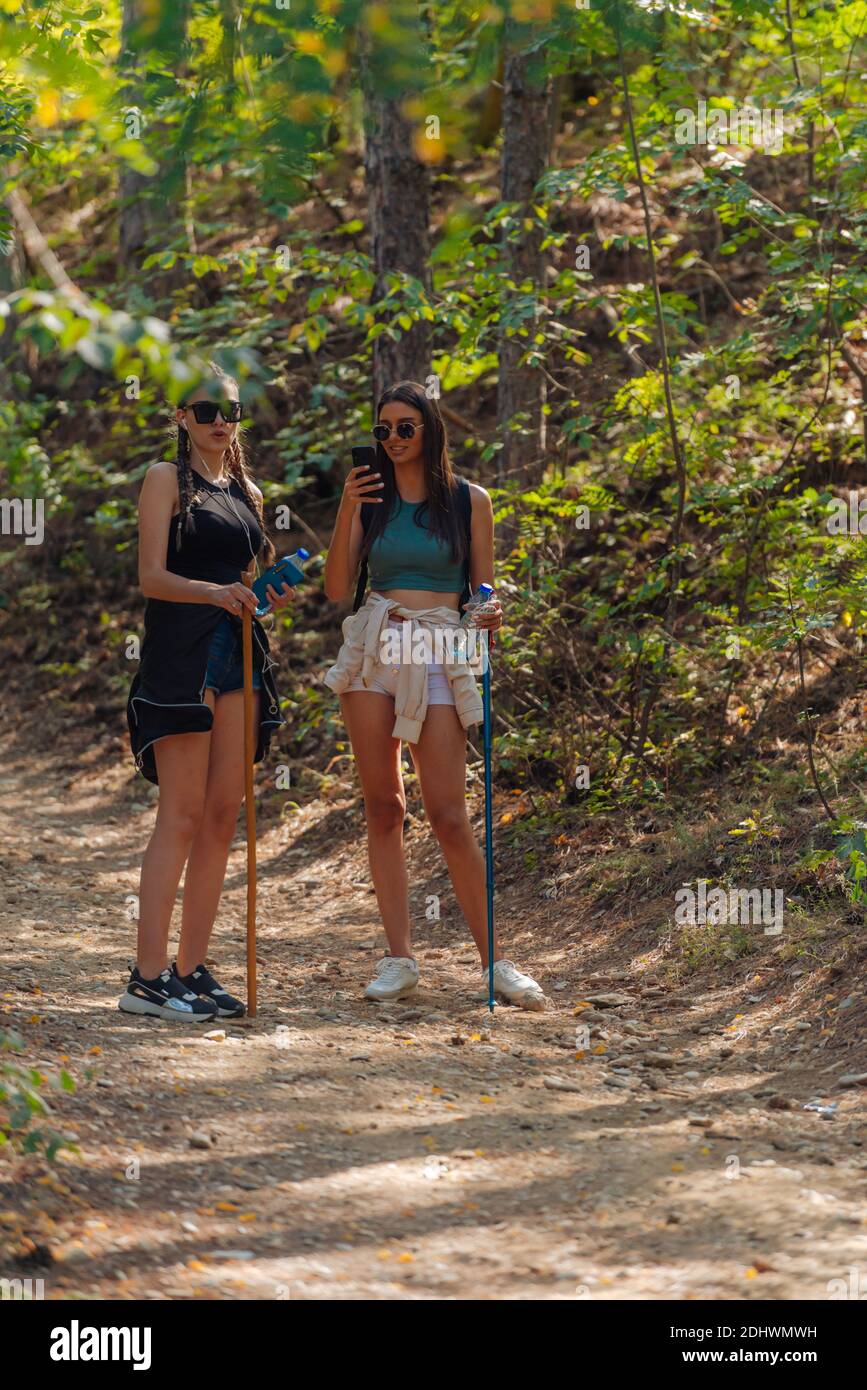 Sisters hiking through beautiful woods while wearing a backpack and ...