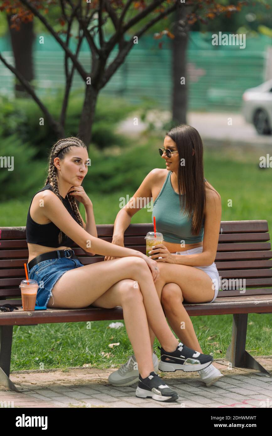 Attractive two women sitting on a park bench on a summer day Stock ...