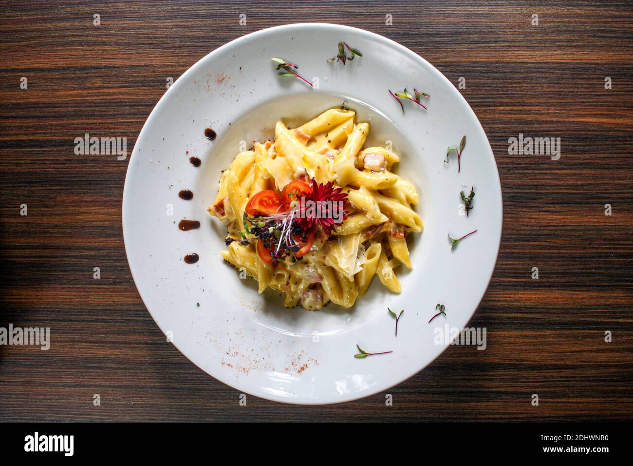 Setting of pasta carbonara made with penne pasta in white plate on ...