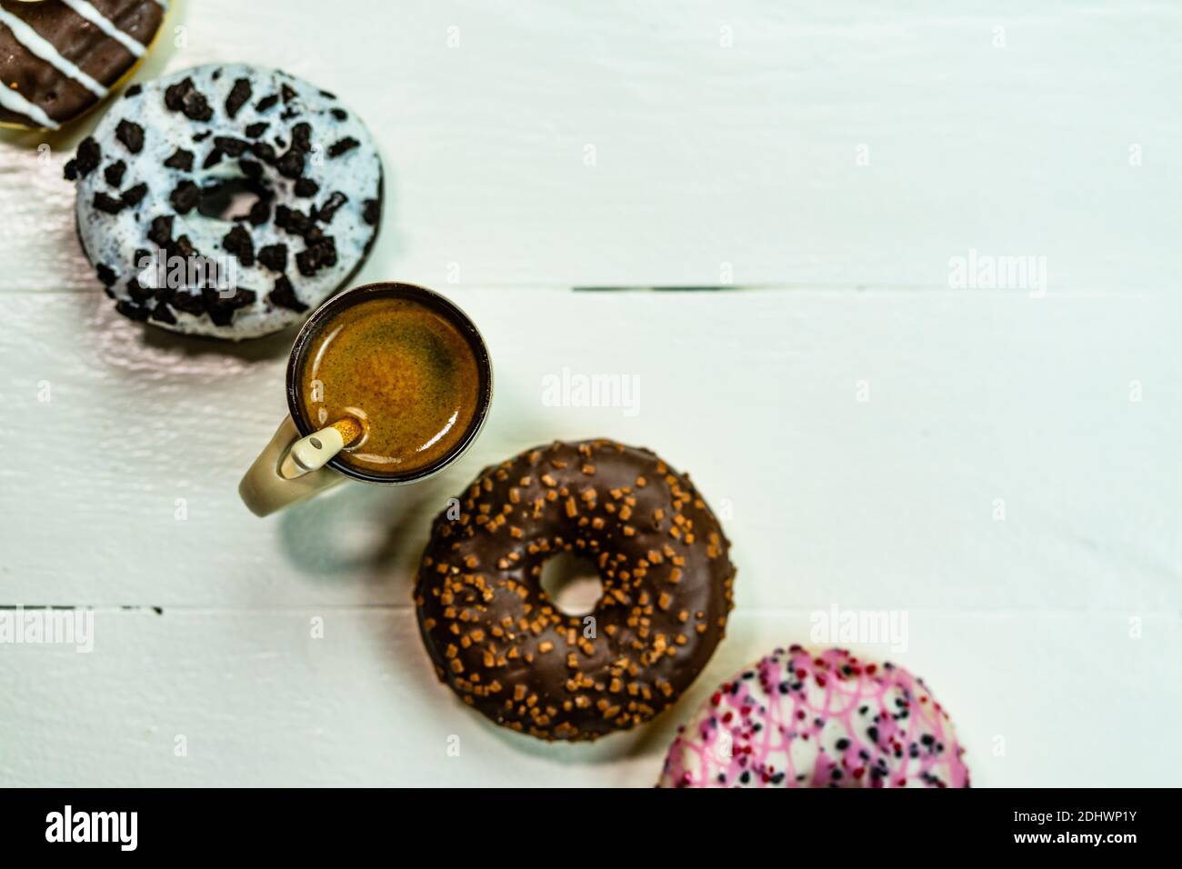 Colorful donuts and coffee cup on white wooden table. Sweet bakery with ...