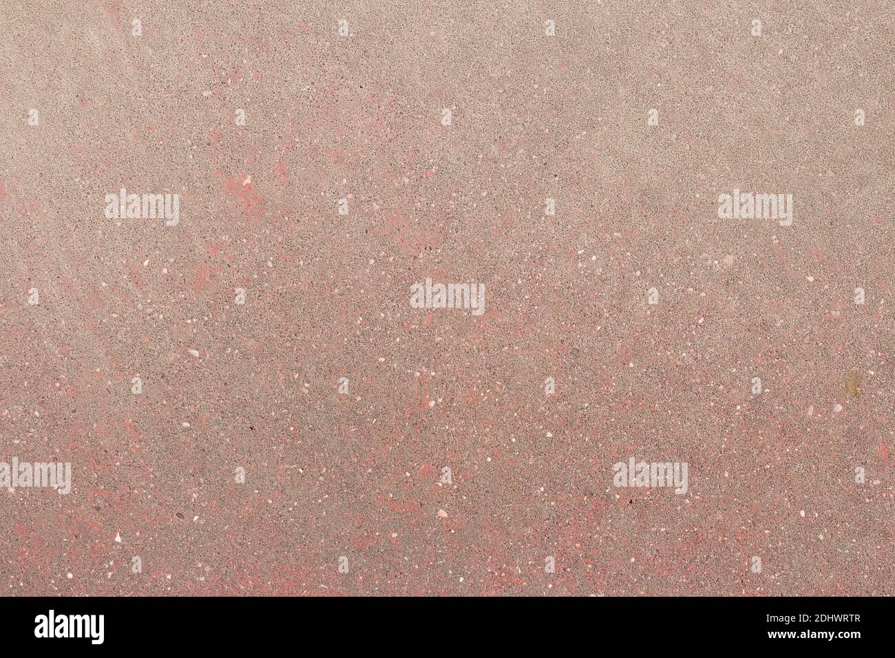Red concrete and worn ground stained with gray dirt and white spots ...