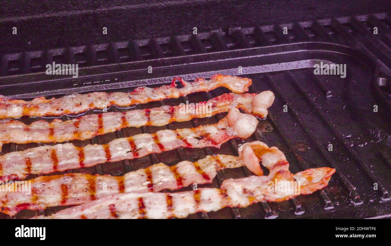 Cooking bacon stips on an outdoor gas grill Stock Photo - Alamy