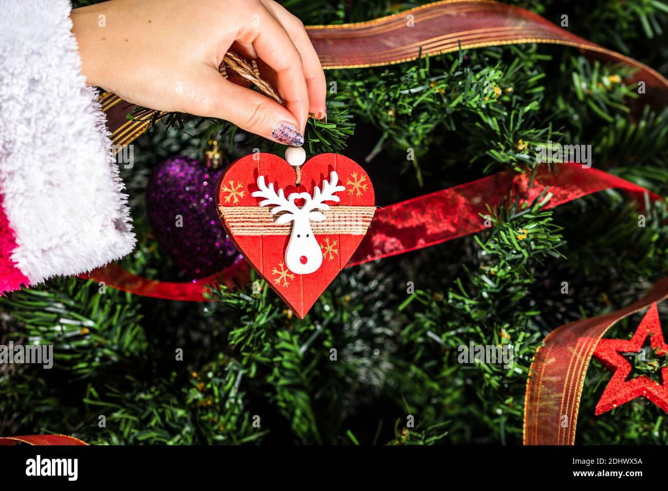 Decorating Christmas tree, hand putting Christmas decorations on fir ...