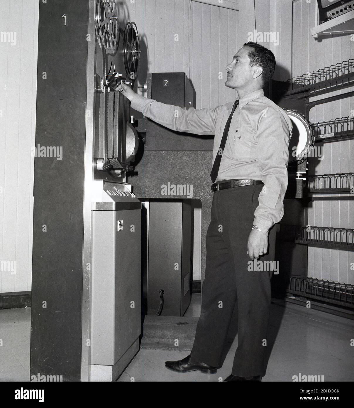 1960s, historical, male studio technician checking the film reels on an ...