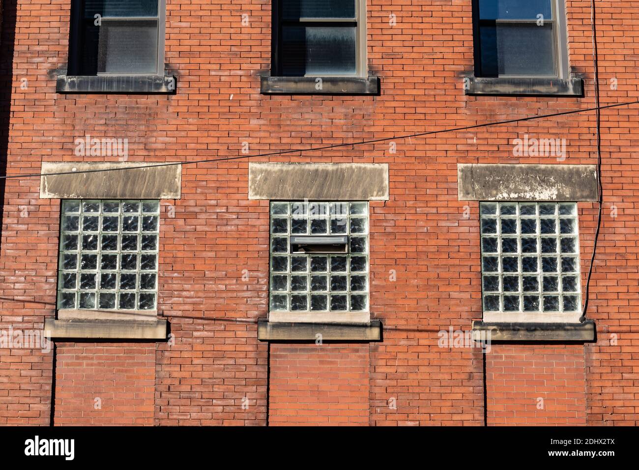 Red brick old commercial industrial building, lower windows with glass ...
