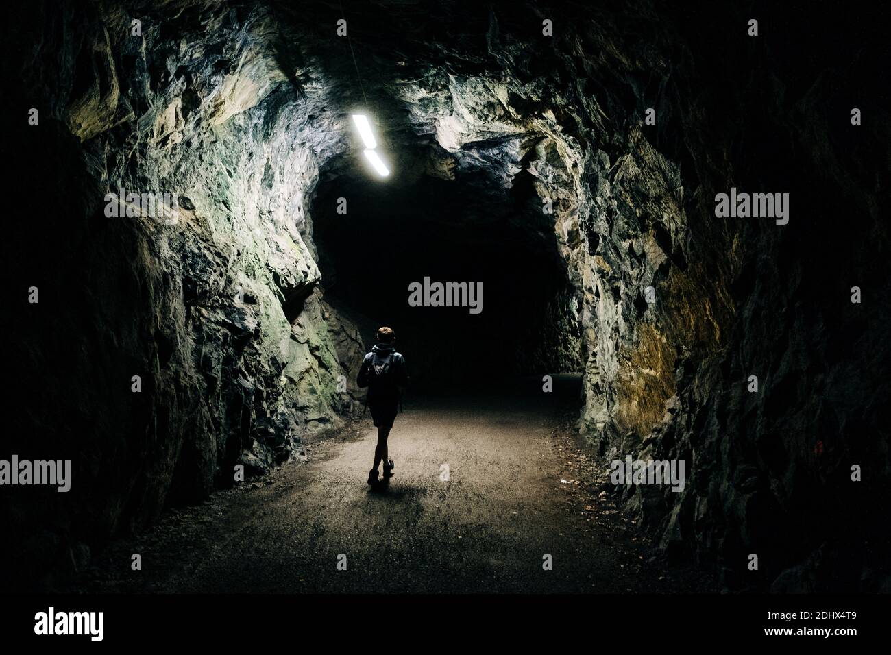 A young man with a backpack walking in a cave Stock Photo - Alamy