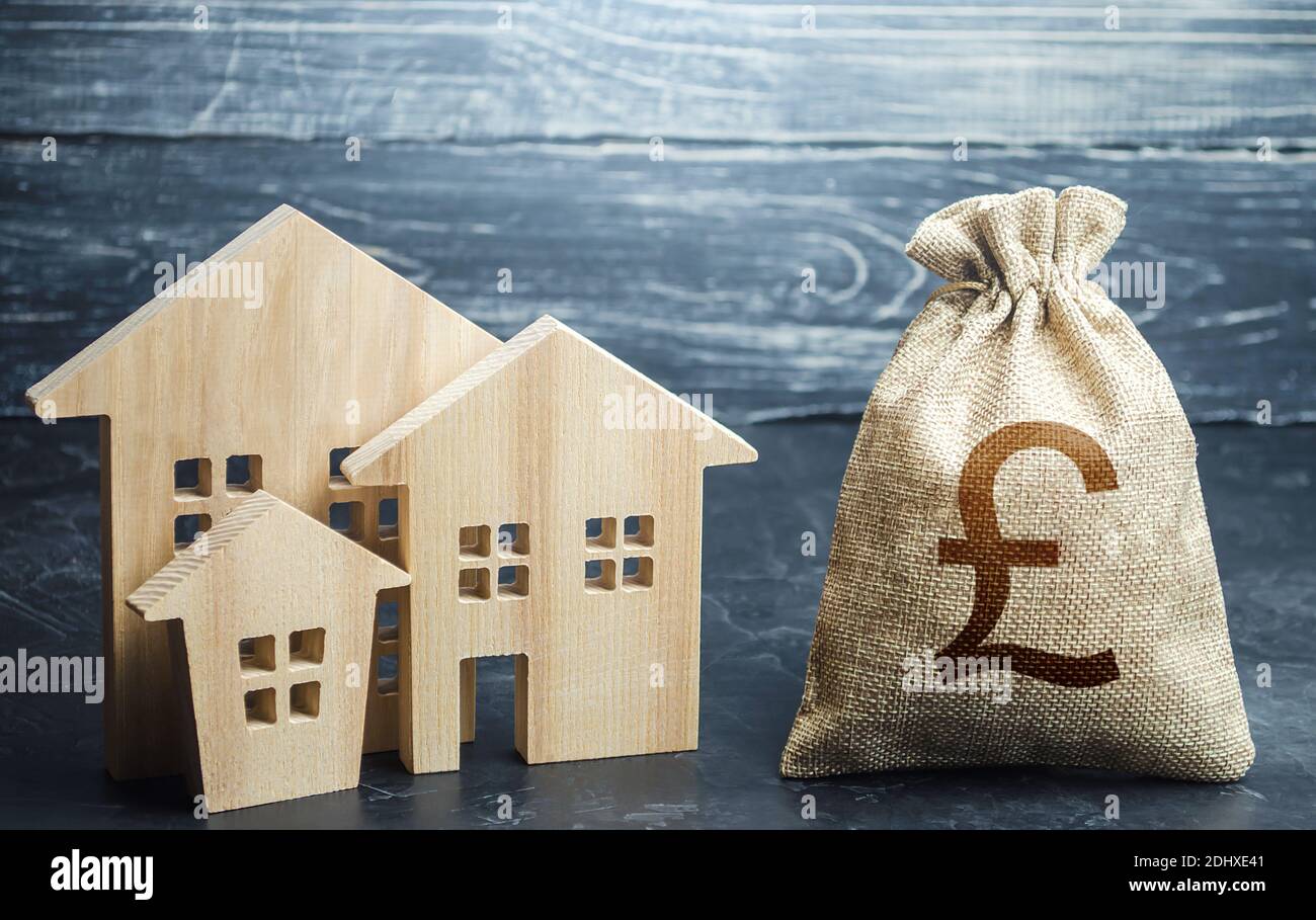 British pound sterling money bag and figurines of residential buildings ...