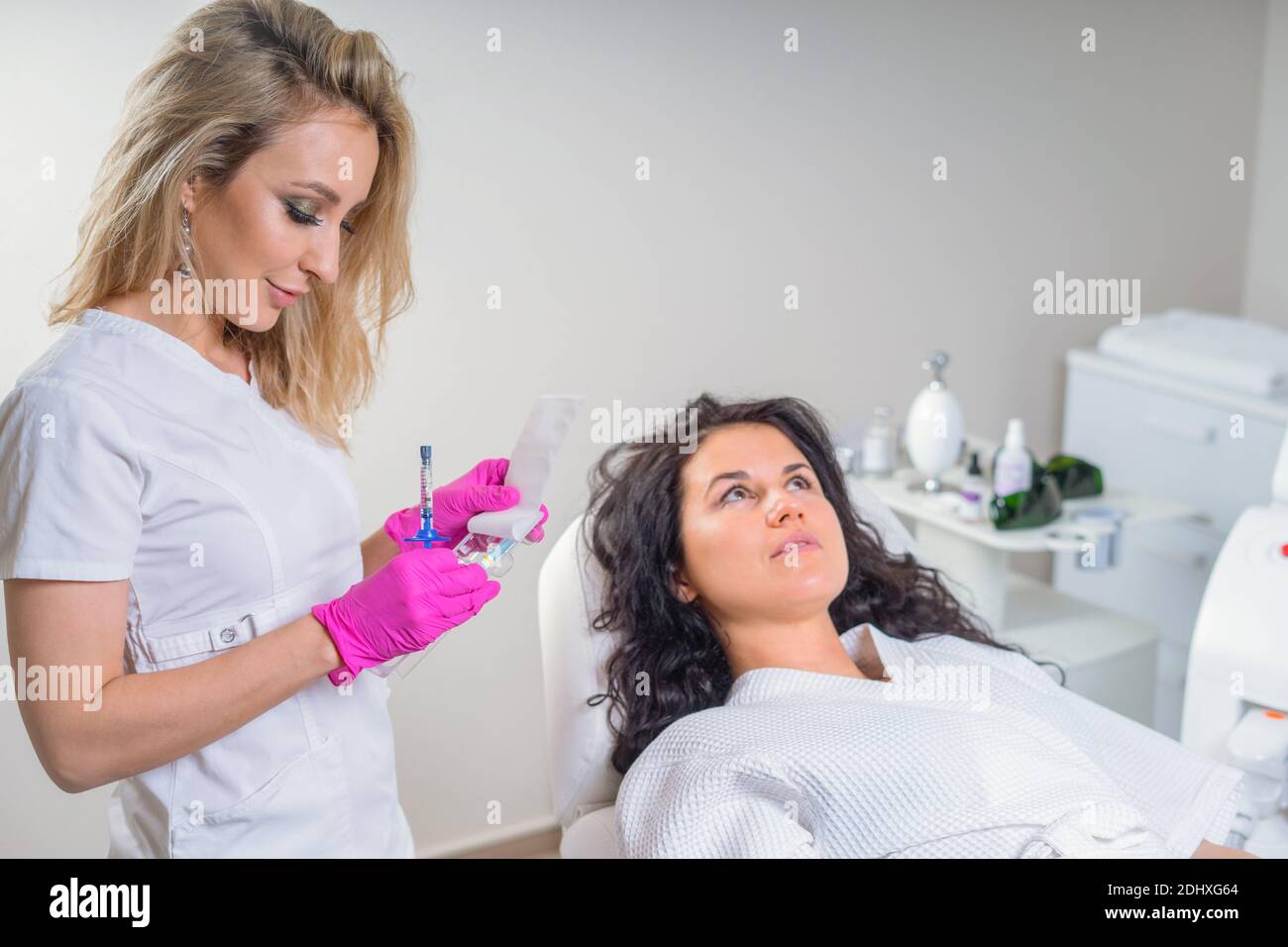 Cosmetologist making face injection with syringe. Young beautiful woman ...