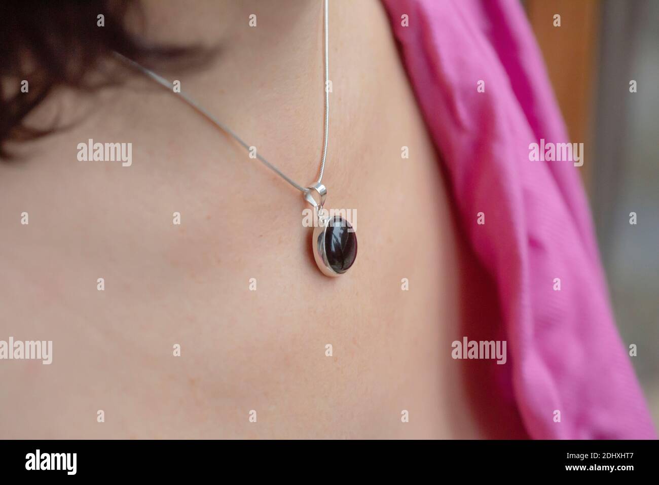 Detail of woman neckline wearing obsidian mineral stone pendant on ...
