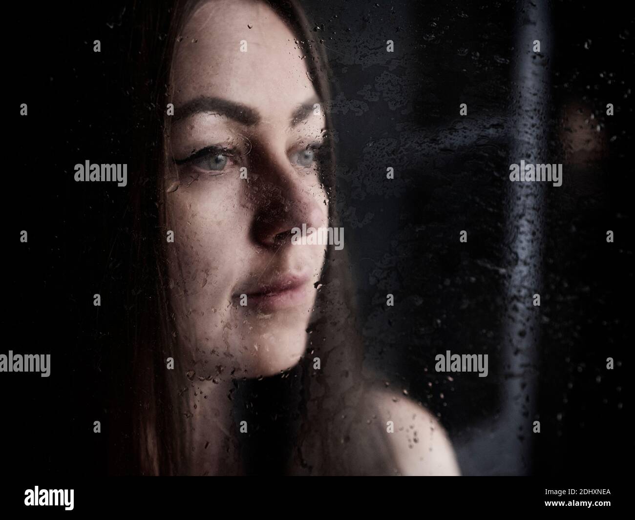Beautiful woman behind wet window Stock Photo - Alamy