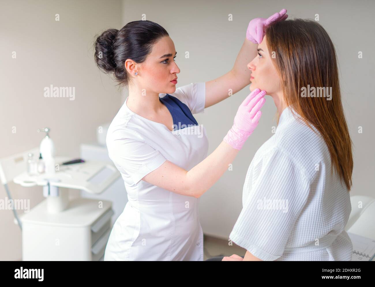 Professional cosmetician examining face skin of girl in clinic of ...