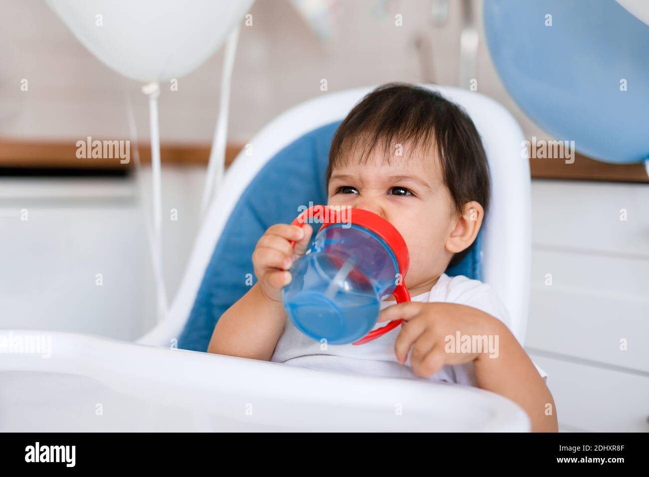 Little baby boy sitting in high chair at home on white kitchen and ...