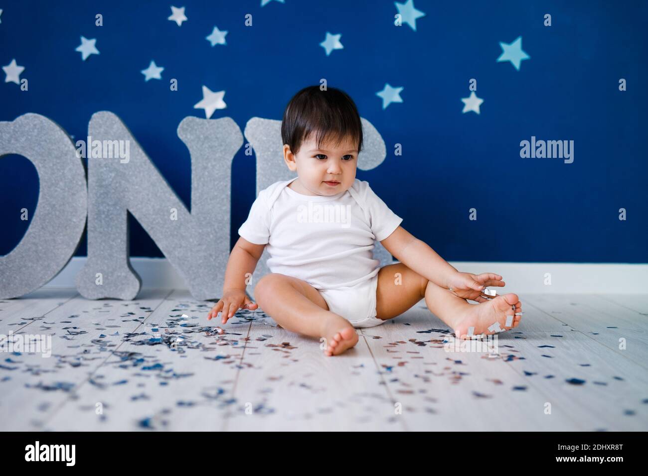 One year old baby boy in white t-shirt celebrates birthday near silver ...