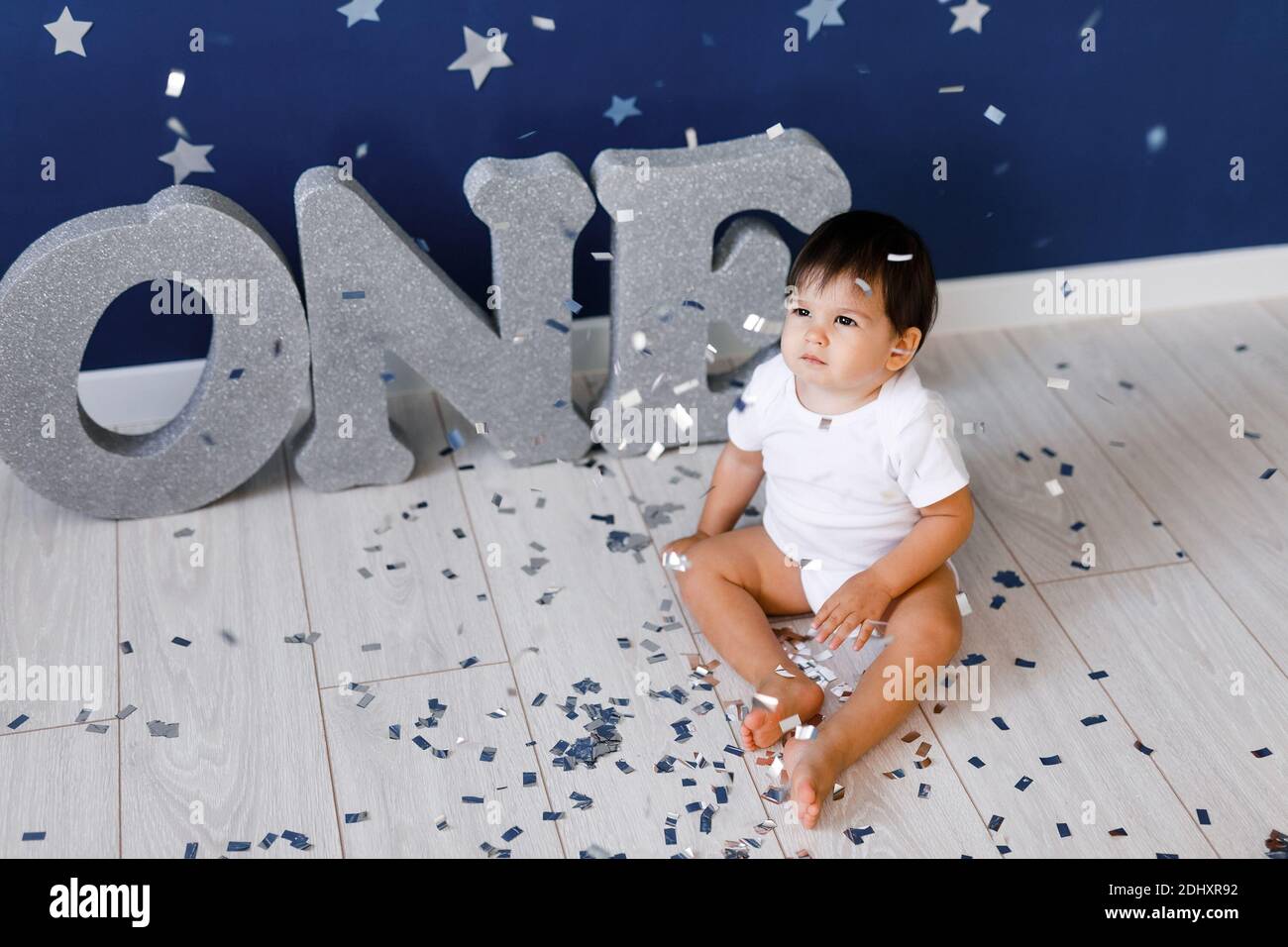 One year old baby boy in white t-shirt celebrates birthday near silver ...