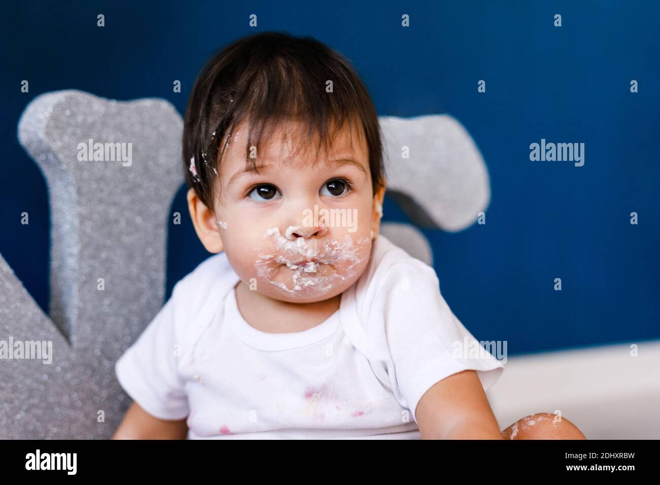 Curious baby boy poking finger in his first birthday cake on blue ...